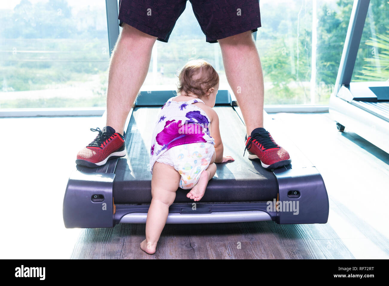 baby crawling on the treadmill in the gym with a view from the window ...