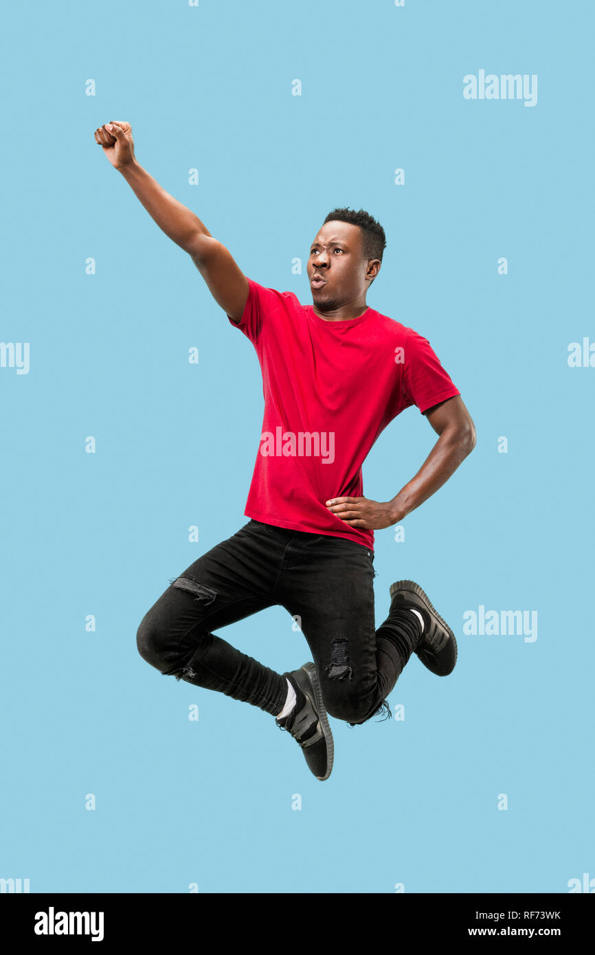 Forward motion. The happy surprised young african man jumping against ...