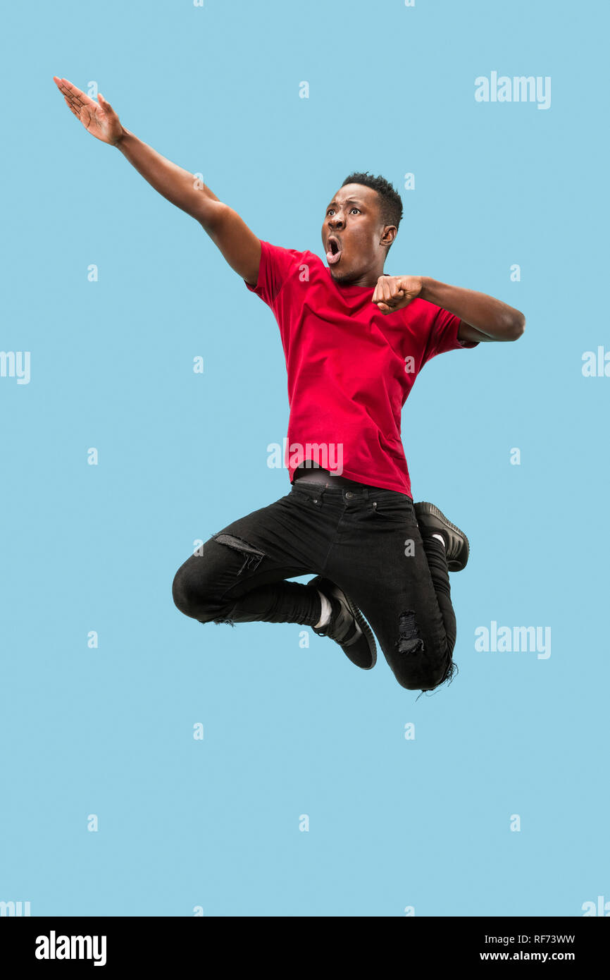 Forward motion. The happy surprised young african man jumping against ...