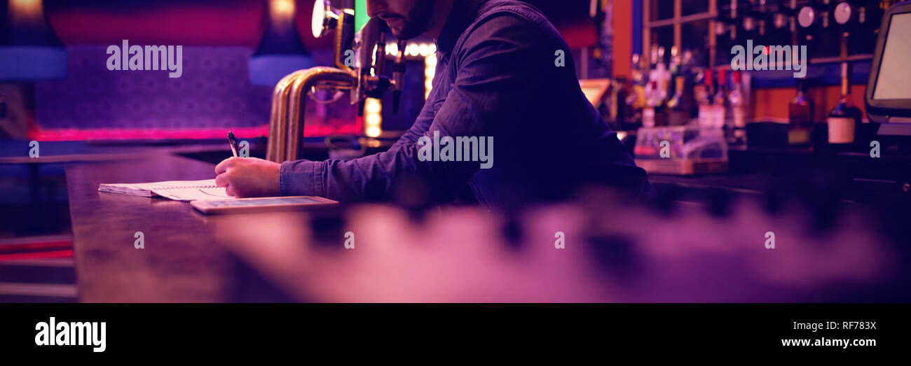 Bartender maintaining records at the counter Stock Photo - Alamy