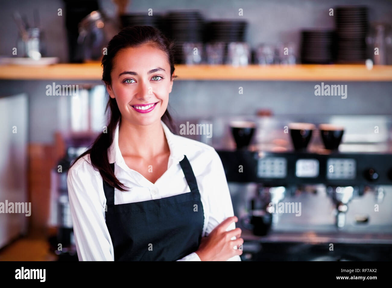 Portrait of smiling waitress standing with arms crossed Stock Photo - Alamy