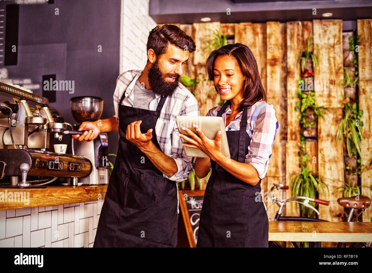 Waitress using a tablet computer and waiter with coffee machine Stock ...