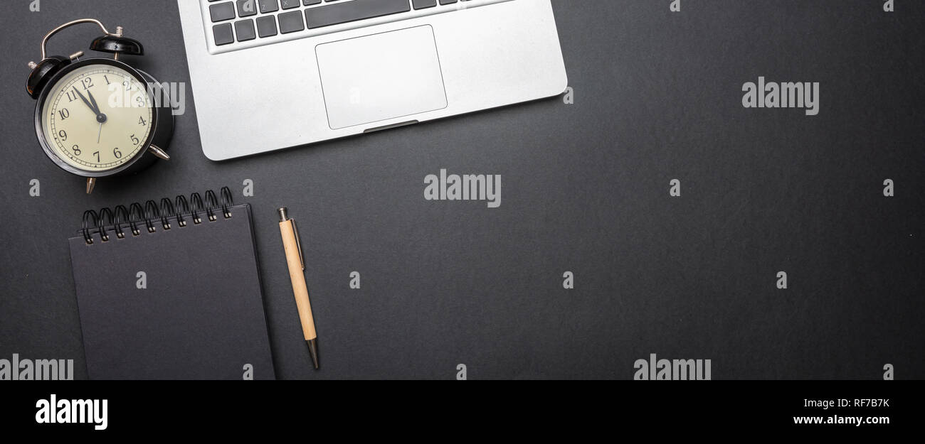 Time management concept. Computer laptop and alarm clock on black color ...