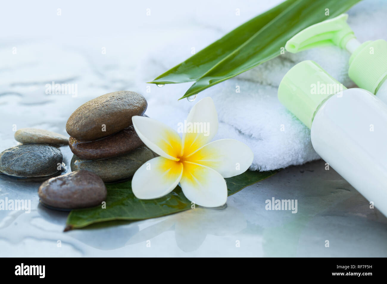 Spa or wellness setting with tropical flowers. Cream tubes on the towel ...