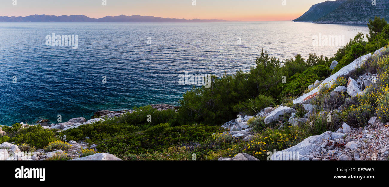Evening summer coastline view with pink sunset and Island on horizon ...