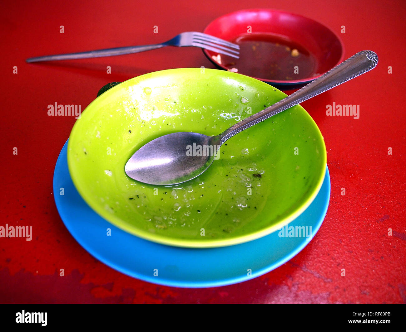 Photo of an empty soup bowl and plate, utensils and some leftover food ...