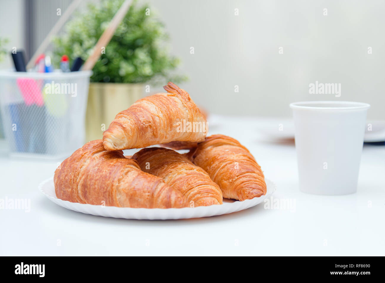 Plain croissants on top of each other on the plate, on white table ...