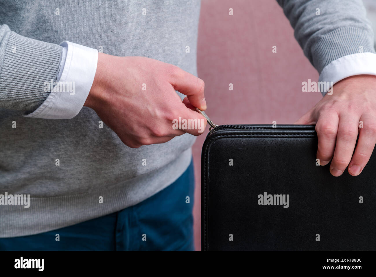 Young business man hand pulling a zipper to close a black leather ...