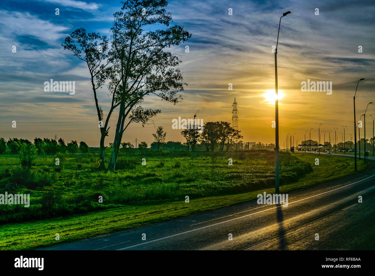 High contrast sunset silhouette field scene from empty highway in ...