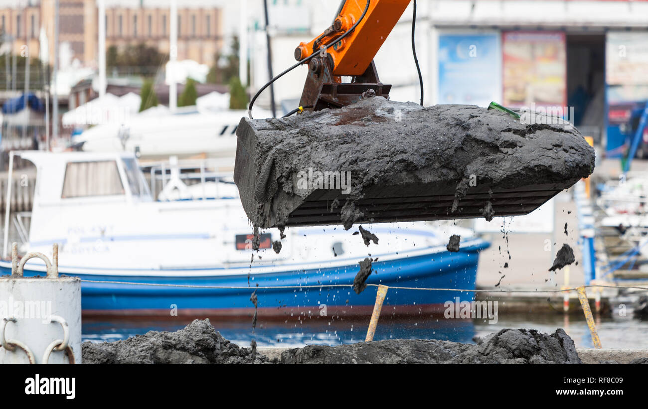 Excavator shovel digging in sand from water. Building construction ...