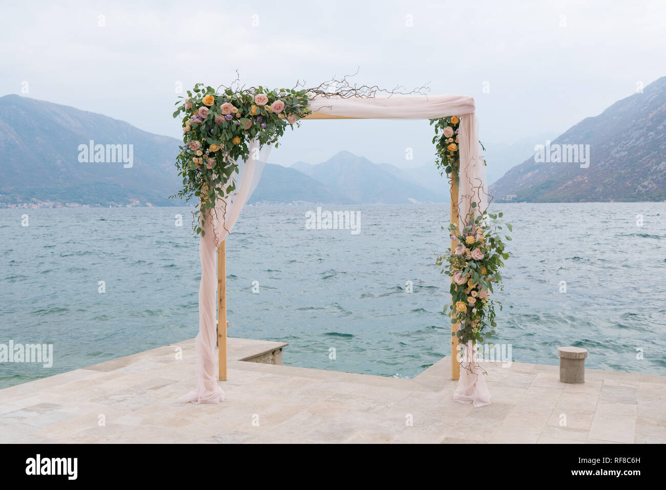 wooden rectangular wedding arch decorated with flowers against the sea ...