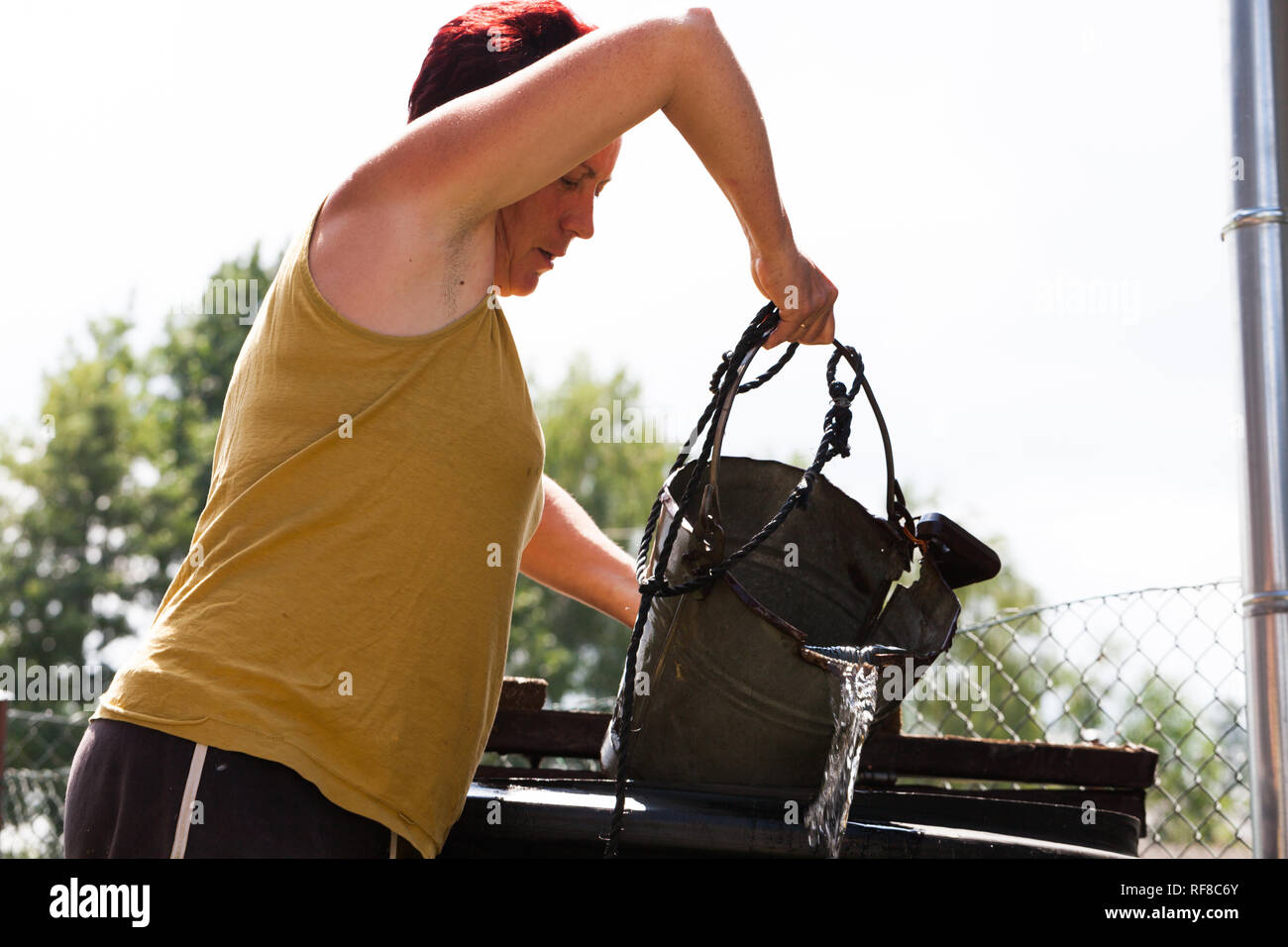 A woman working hard fetching water from the natural well. The middle ...
