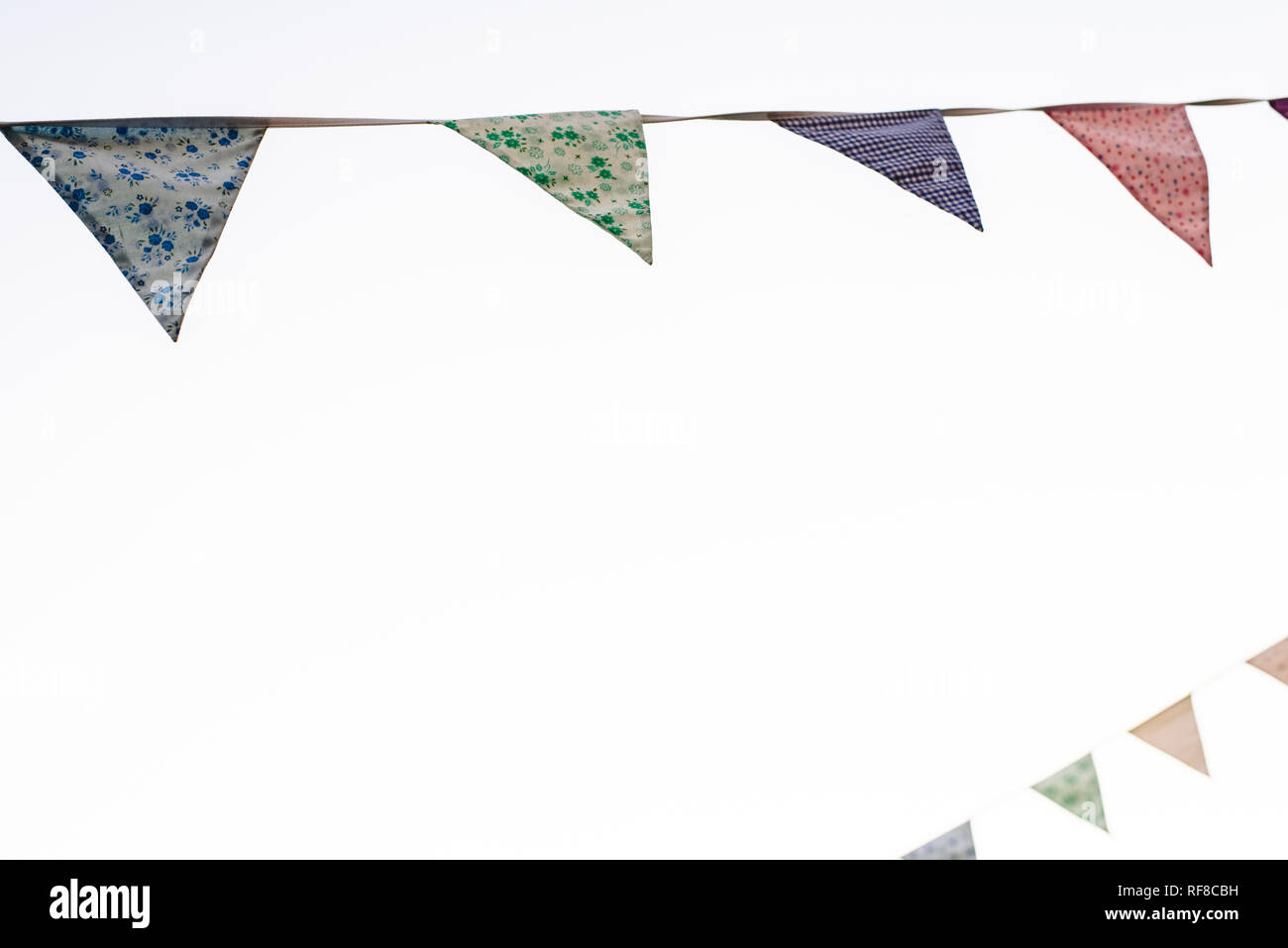 Pennants with blue sky background and pale colors hanging on a rope ...