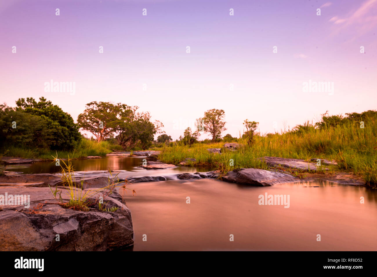 A river flowing over rocks, surrounded by boulders and green grass ...