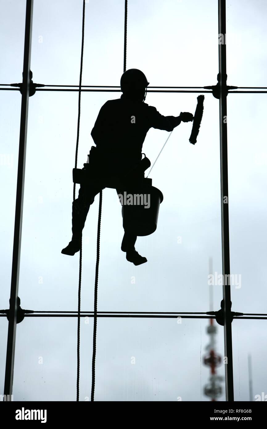 Window washer hanging against the glass facade of a skyscraper, Tokyo ...