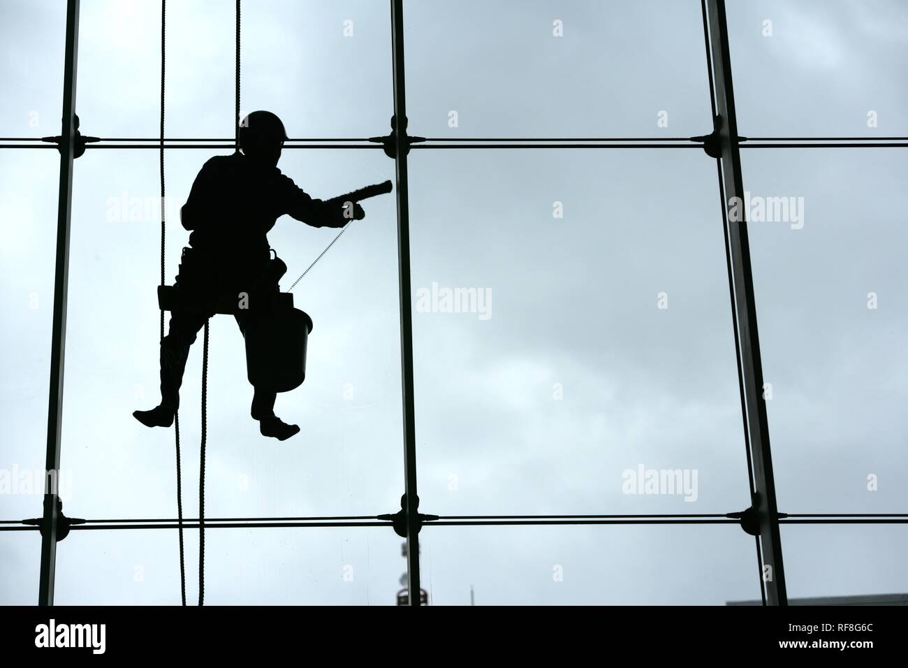 Window washer hanging against the glass facade of a skyscraper, Tokyo ...