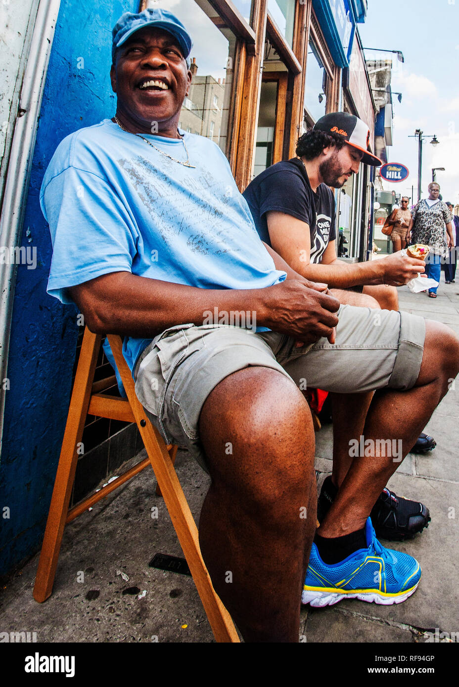 Black man seated in shorts and baseball hat hi-res stock photography ...