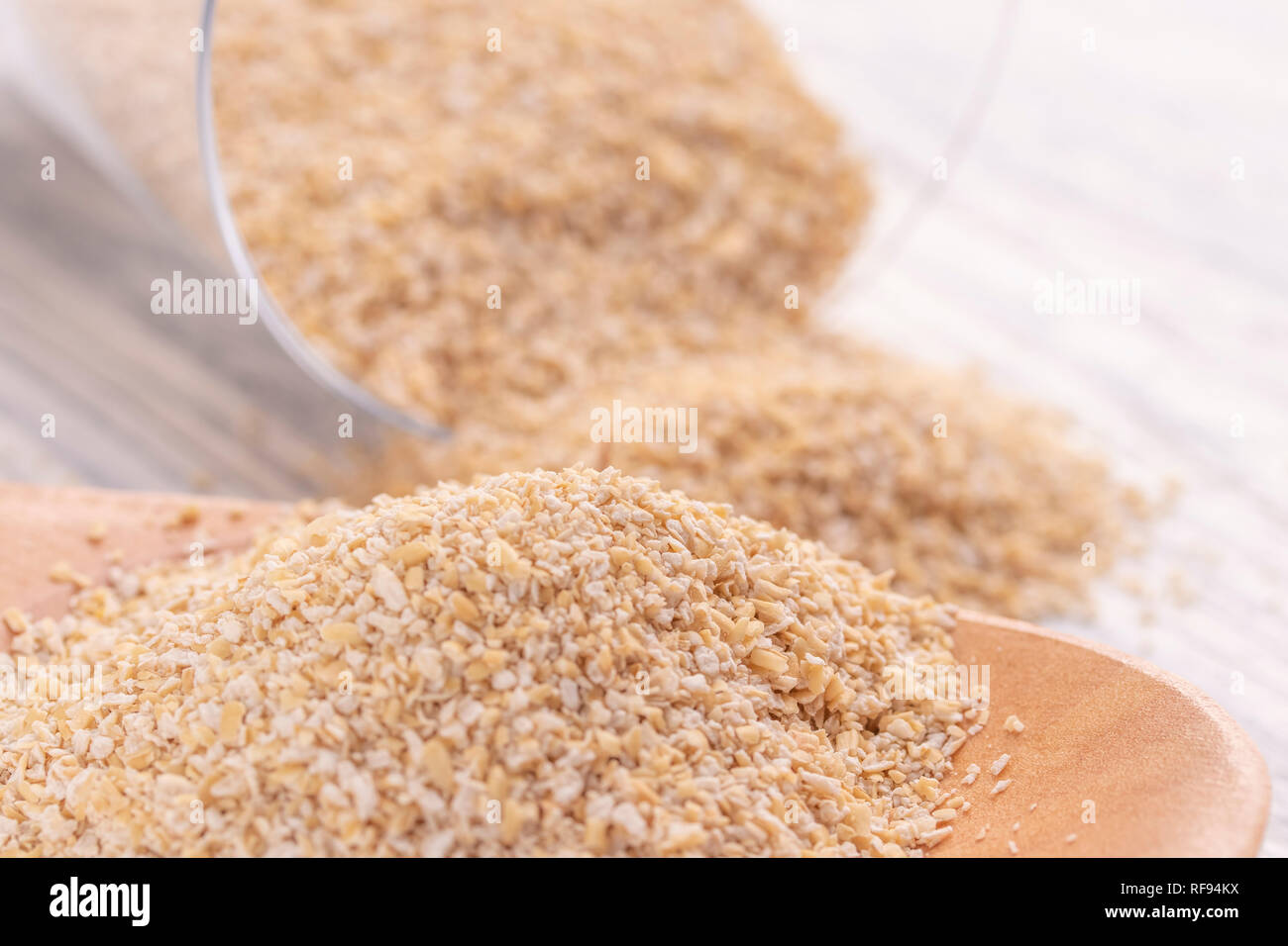 Oat bran in a wooden spoon and in a glass transparent glass on a white ...