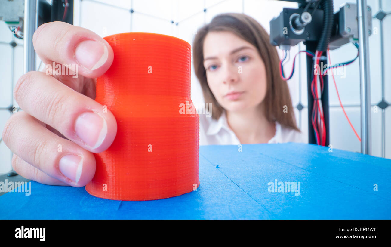 Young women designer in 3d printing lab. Girl takes the finished detail ...