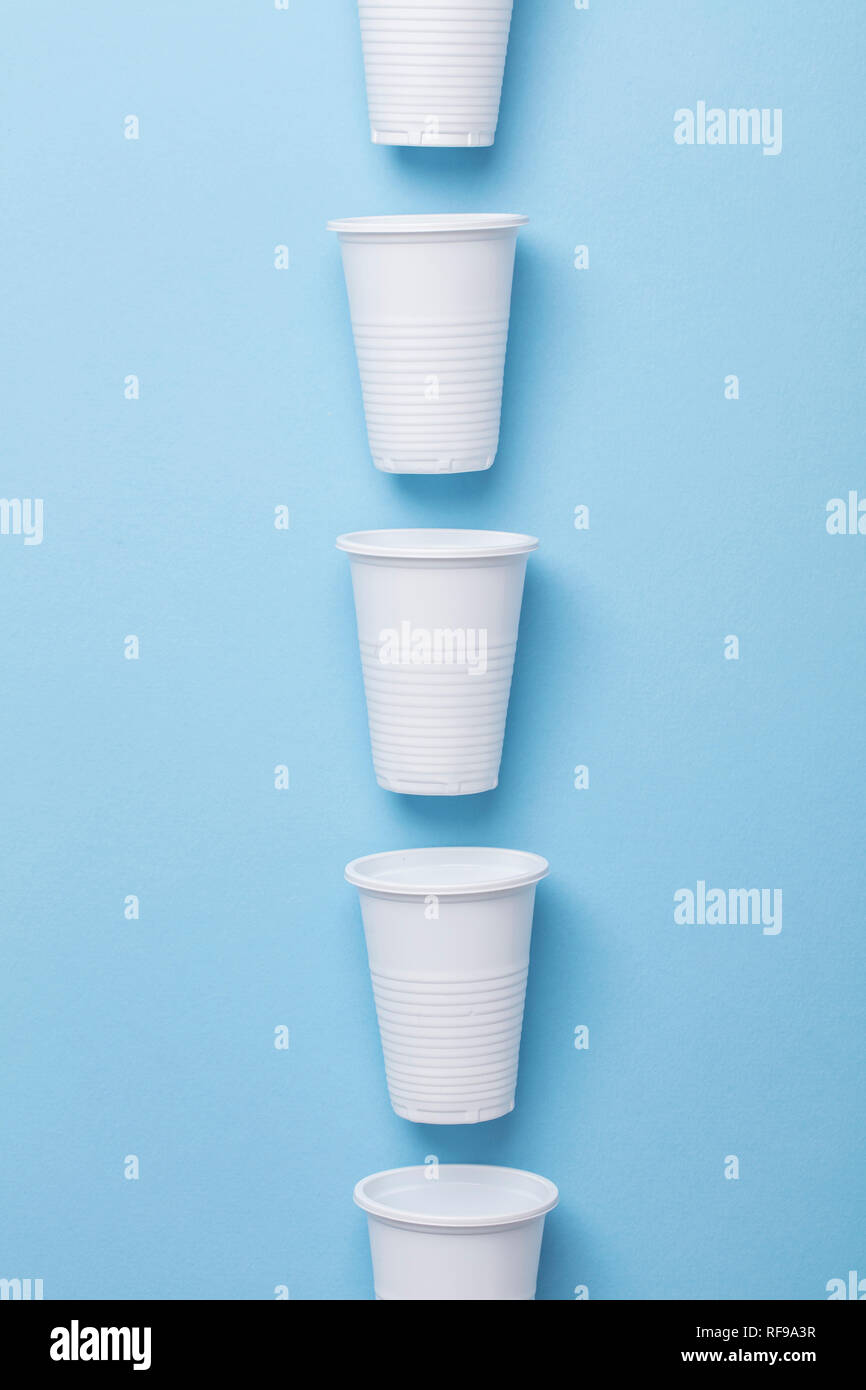 Single use white plastic cups on a blue background Stock Photo - Alamy