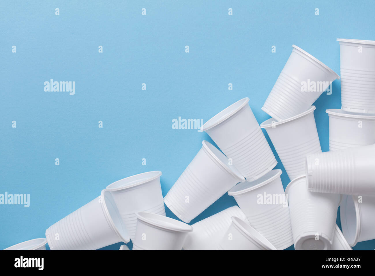 Single use white plastic cups on a blue background Stock Photo - Alamy