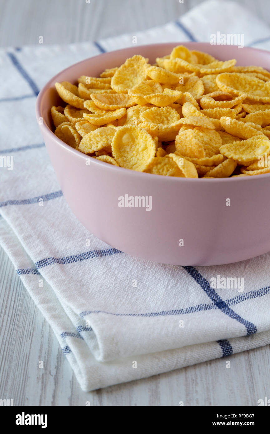 Corn flakes in a pink bowl for breakfast over white wooden background ...