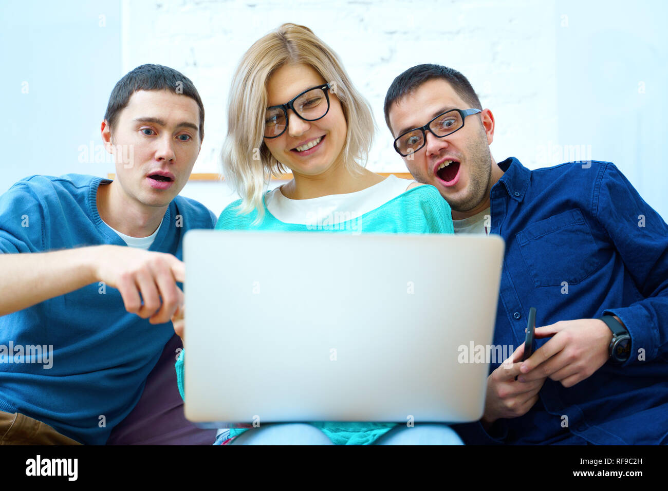Friends sit on the couch, chatting and using a smartphone, desktop ...