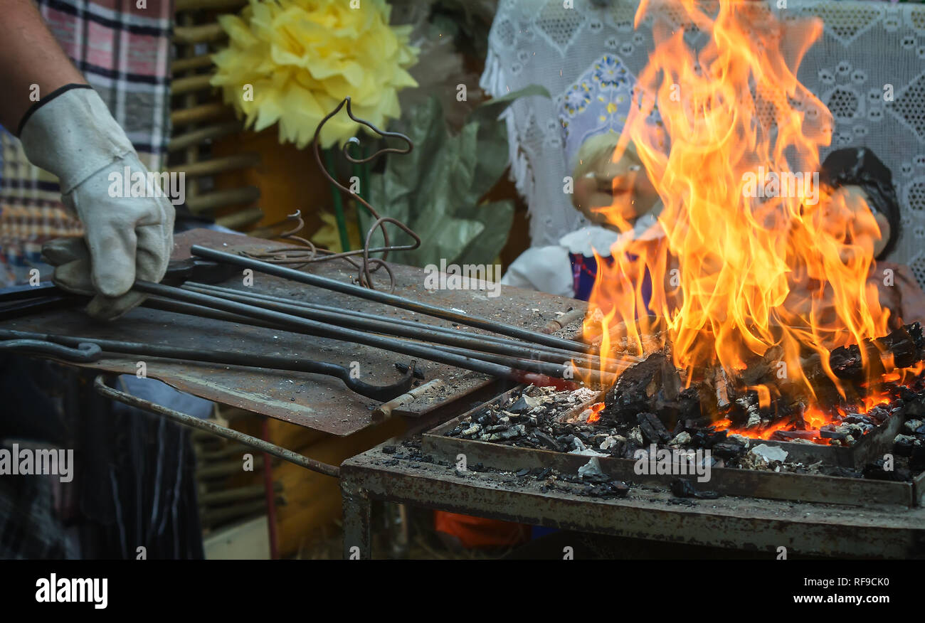 In a small mobile forge at the fair the blacksmith makes forged ...