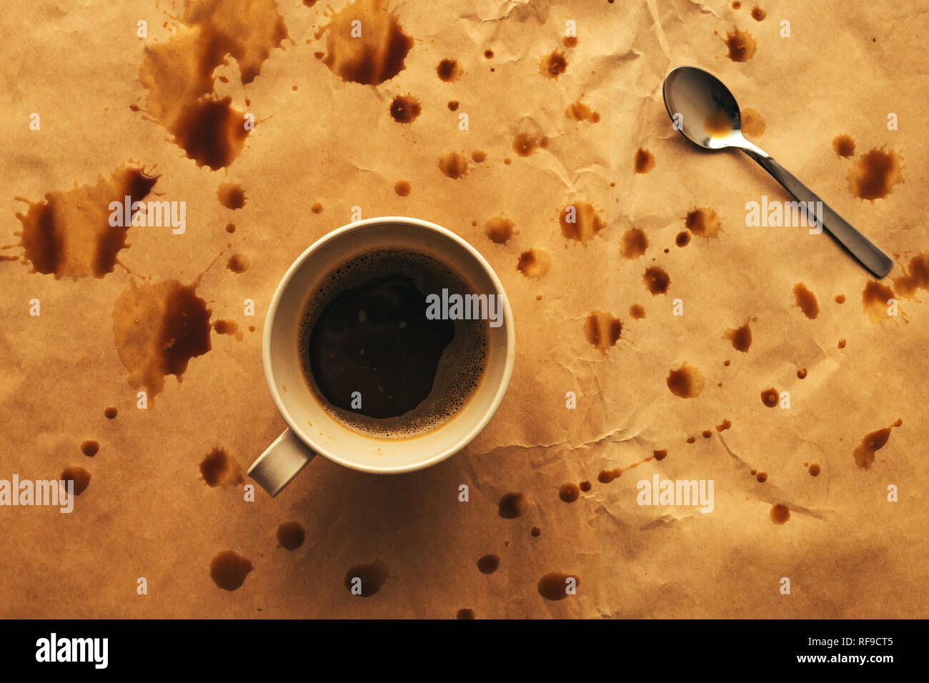 Top view of coffee cup and spoon with splashes, stains and drips on ...