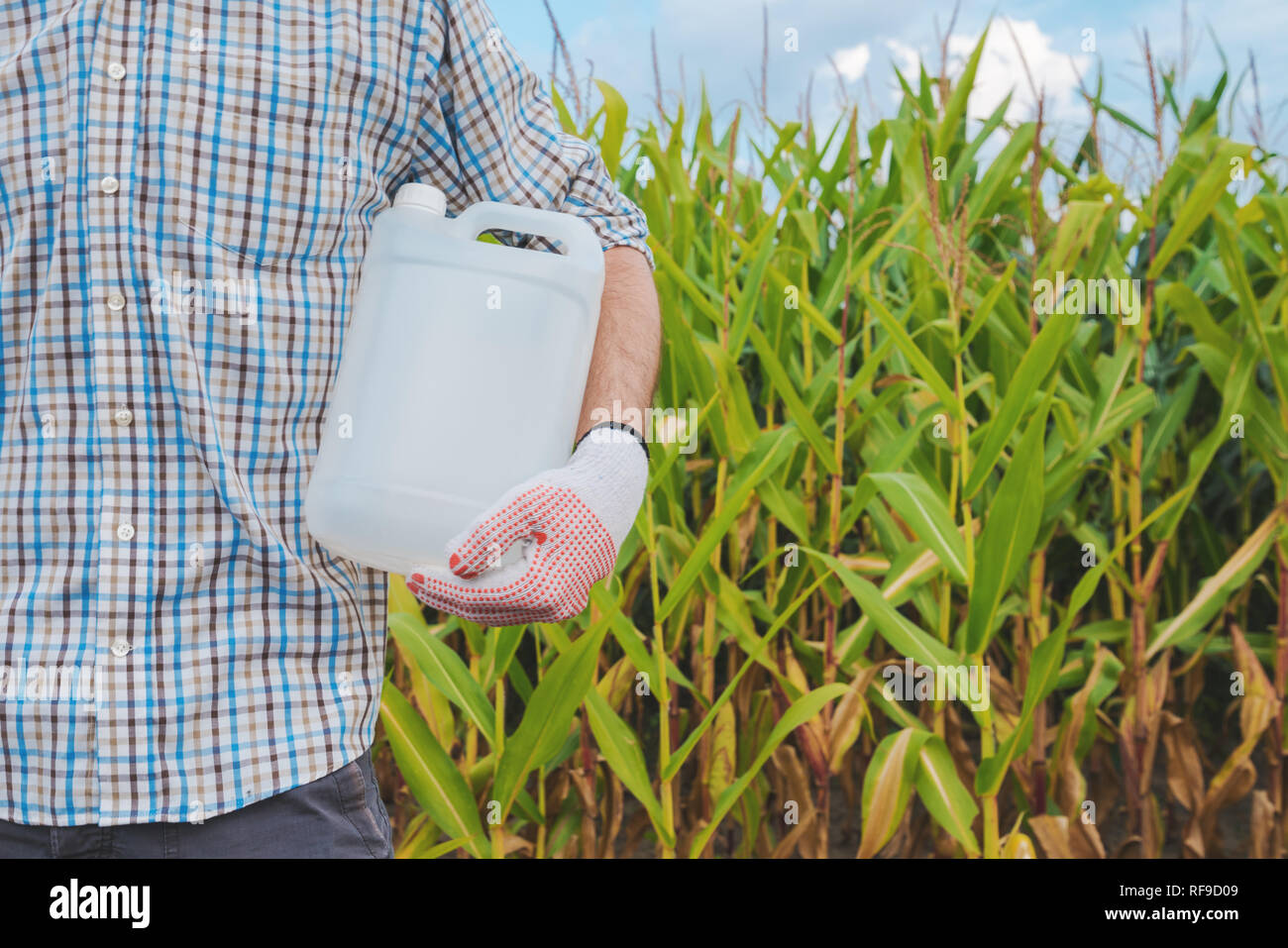 Farmer holding unlabeled pesticide jug in field, agronomist recommends ...