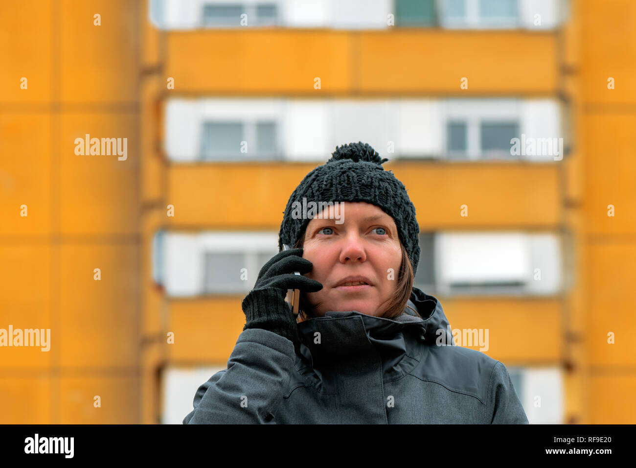 Woman talking on mobile phone on street in winter. Serious caucasian ...