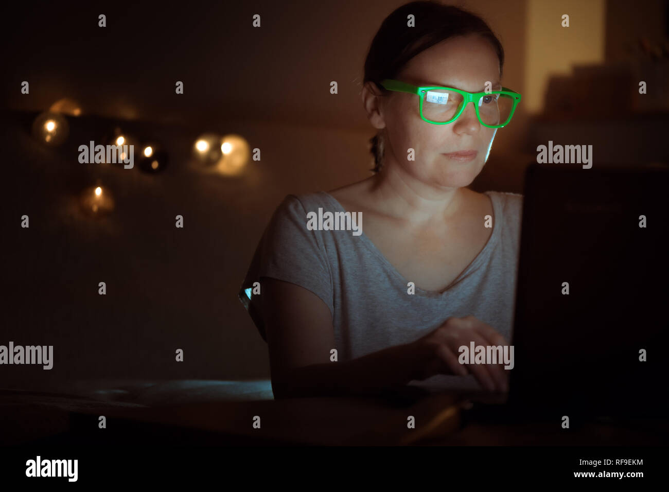 Woman working overtime on laptop computer late at night, low key ...