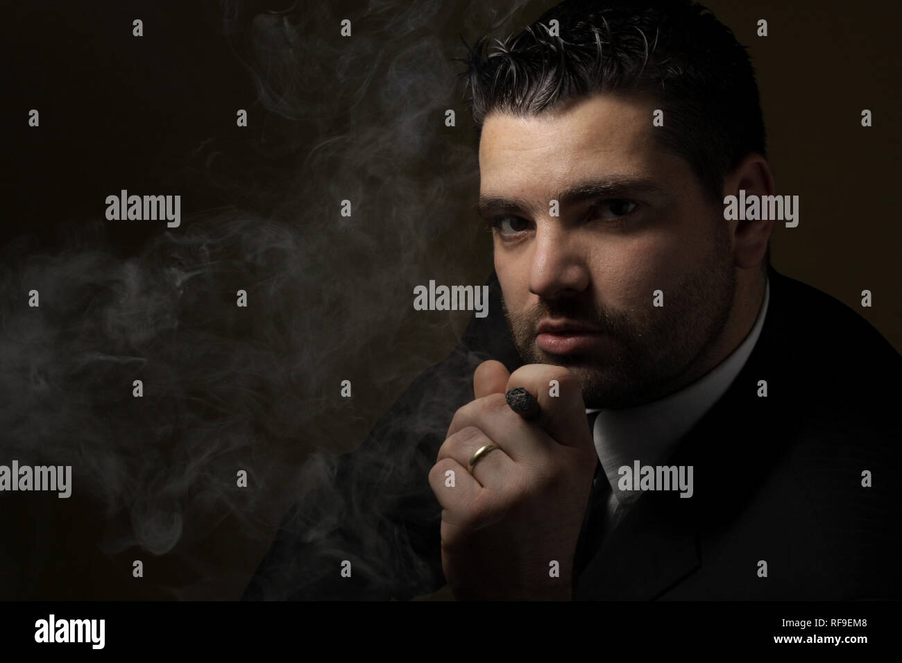 Low key portrait of a man smoking a cigar Stock Photo - Alamy