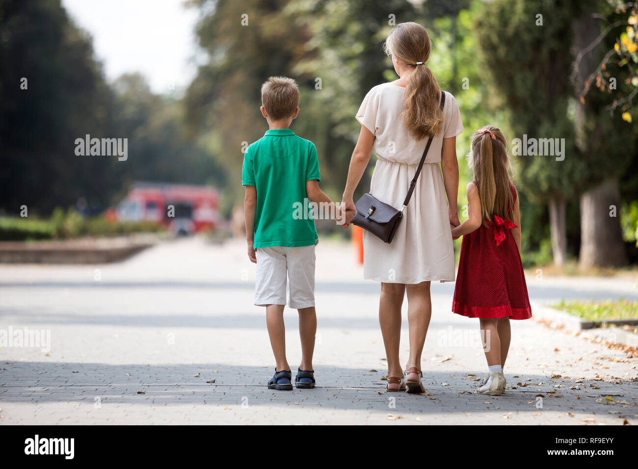 Back view of happy family, young blond long-haired woman walking ...
