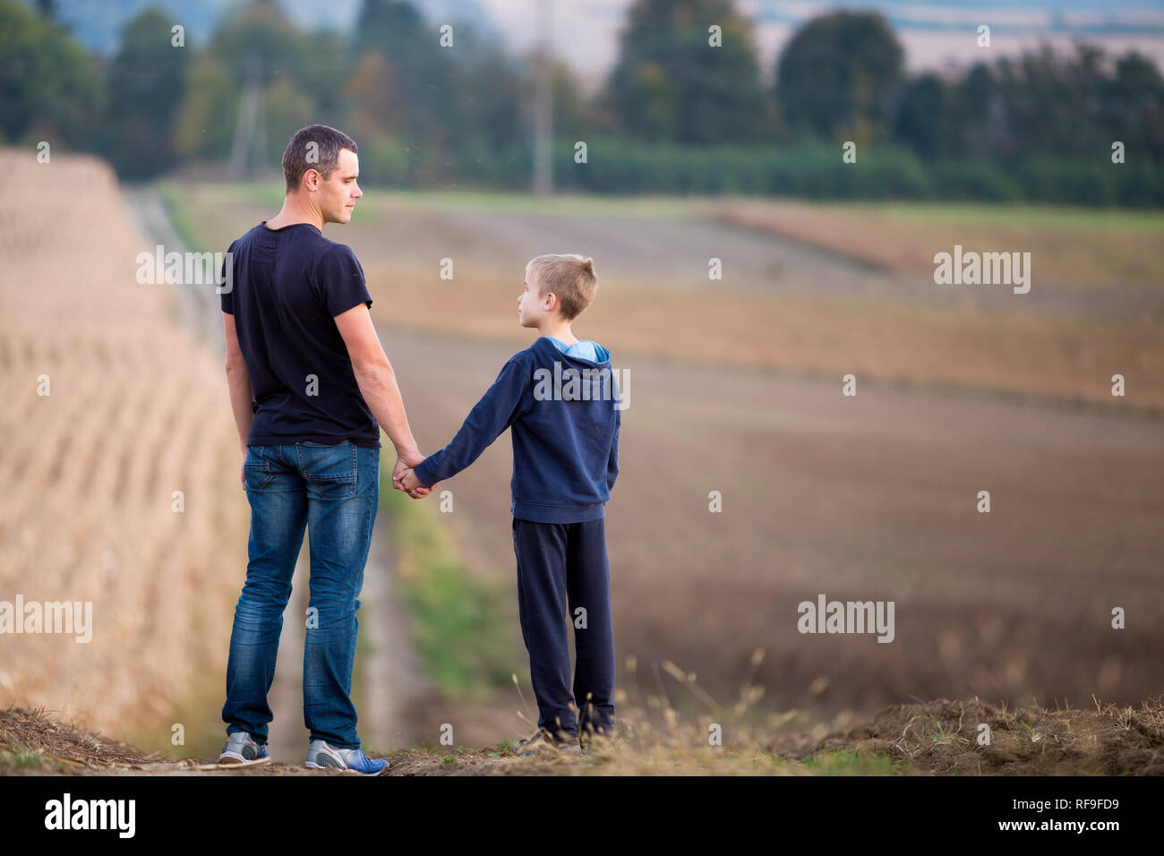 Profile portrait of young father and smiling son standing in grassy ...