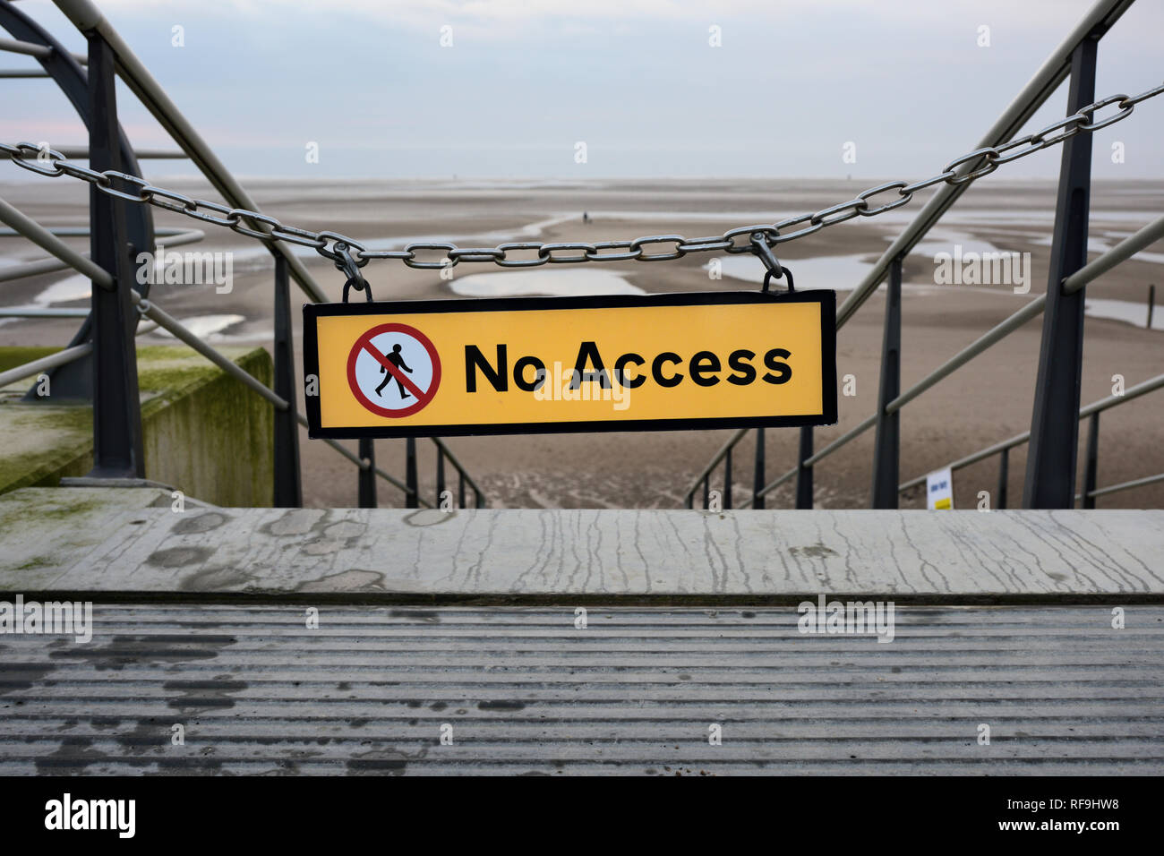 No access sign and chain barrier on promenade with beach in background ...