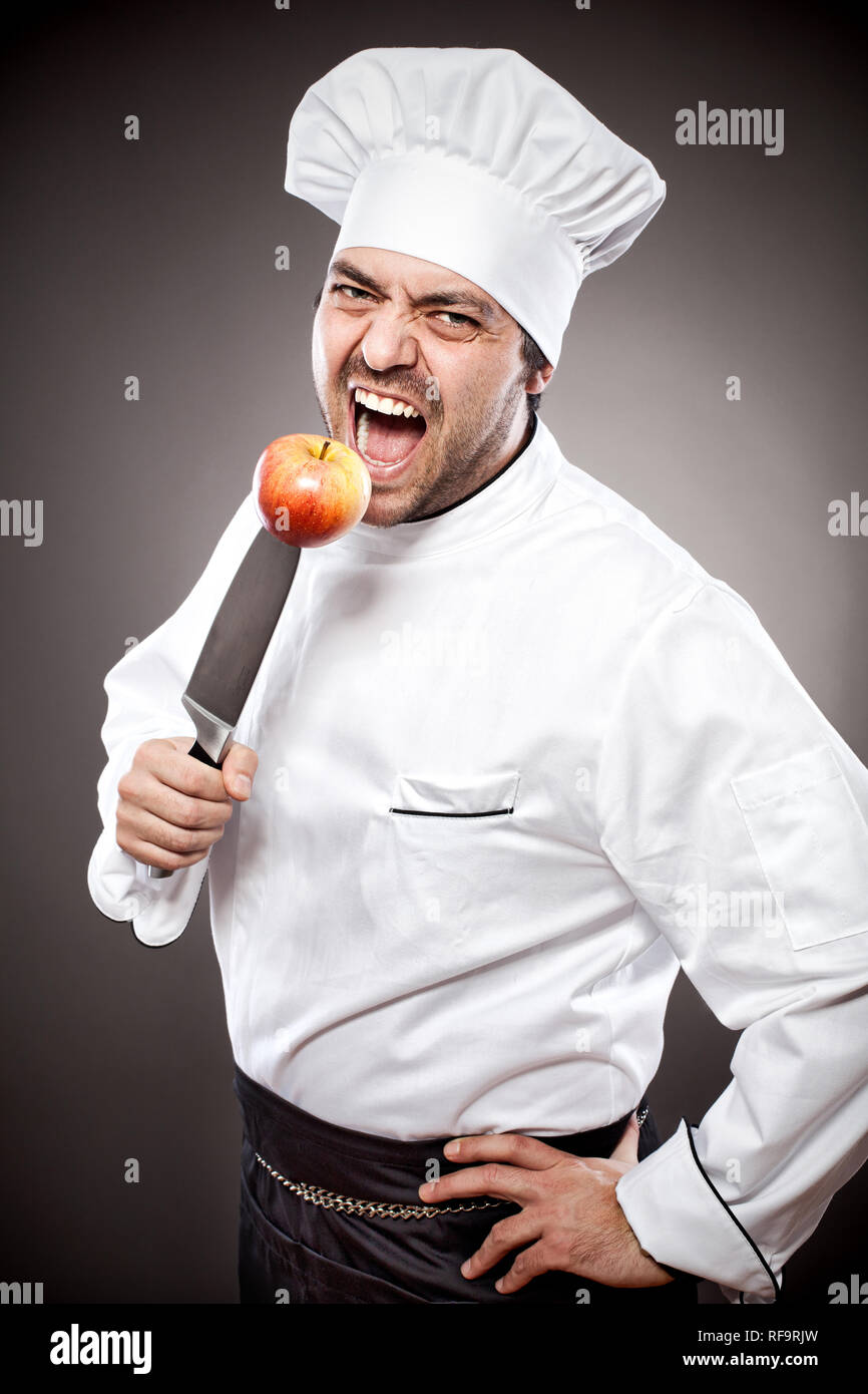 Chef with knife posing against gray background Stock Photo - Alamy