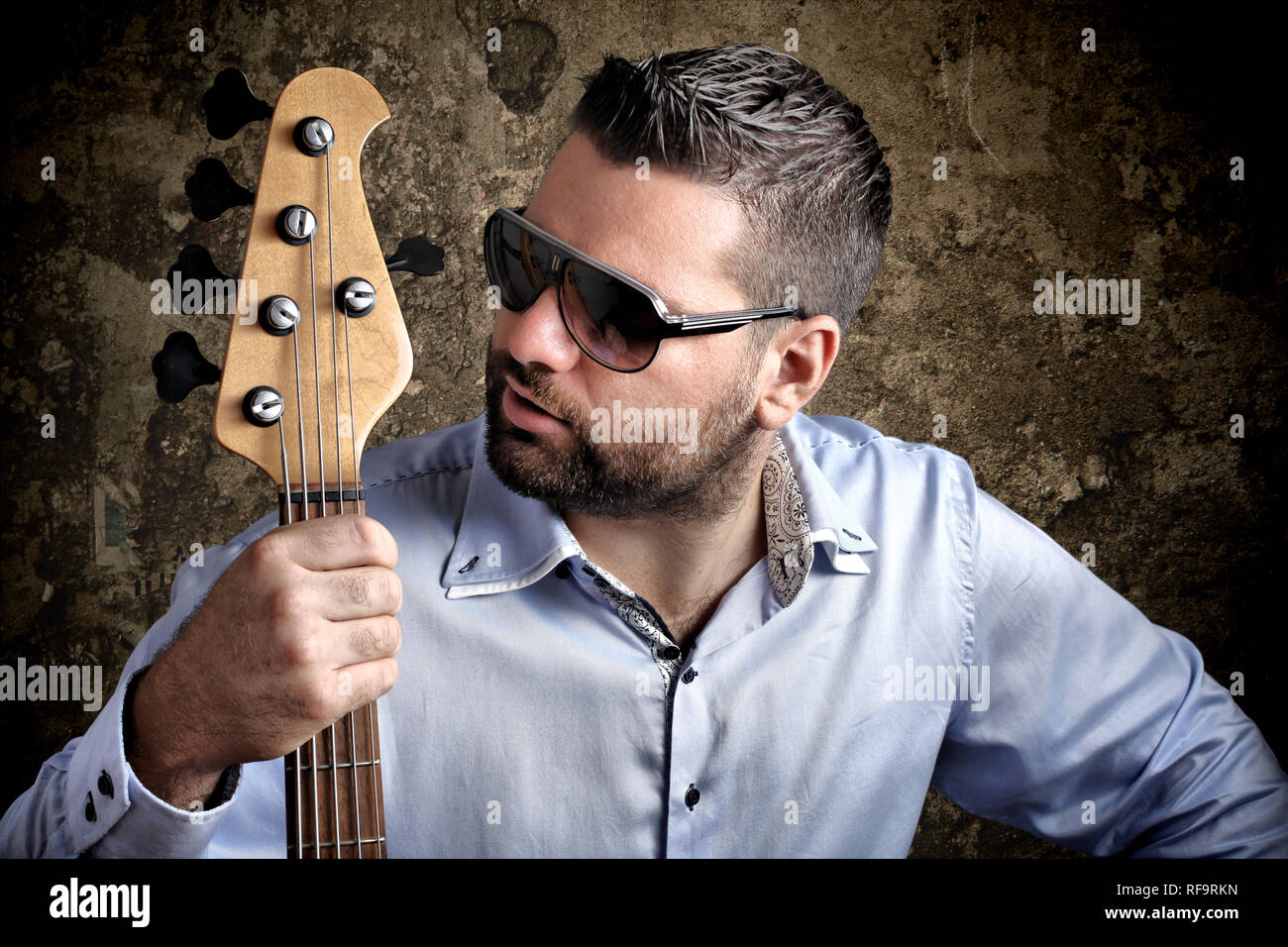 Bass player with glasses against grungy background Stock Photo - Alamy