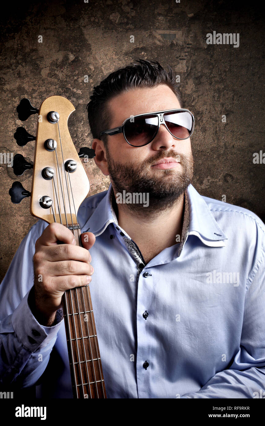 Bass player with glasses posing against grungy background Stock Photo ...