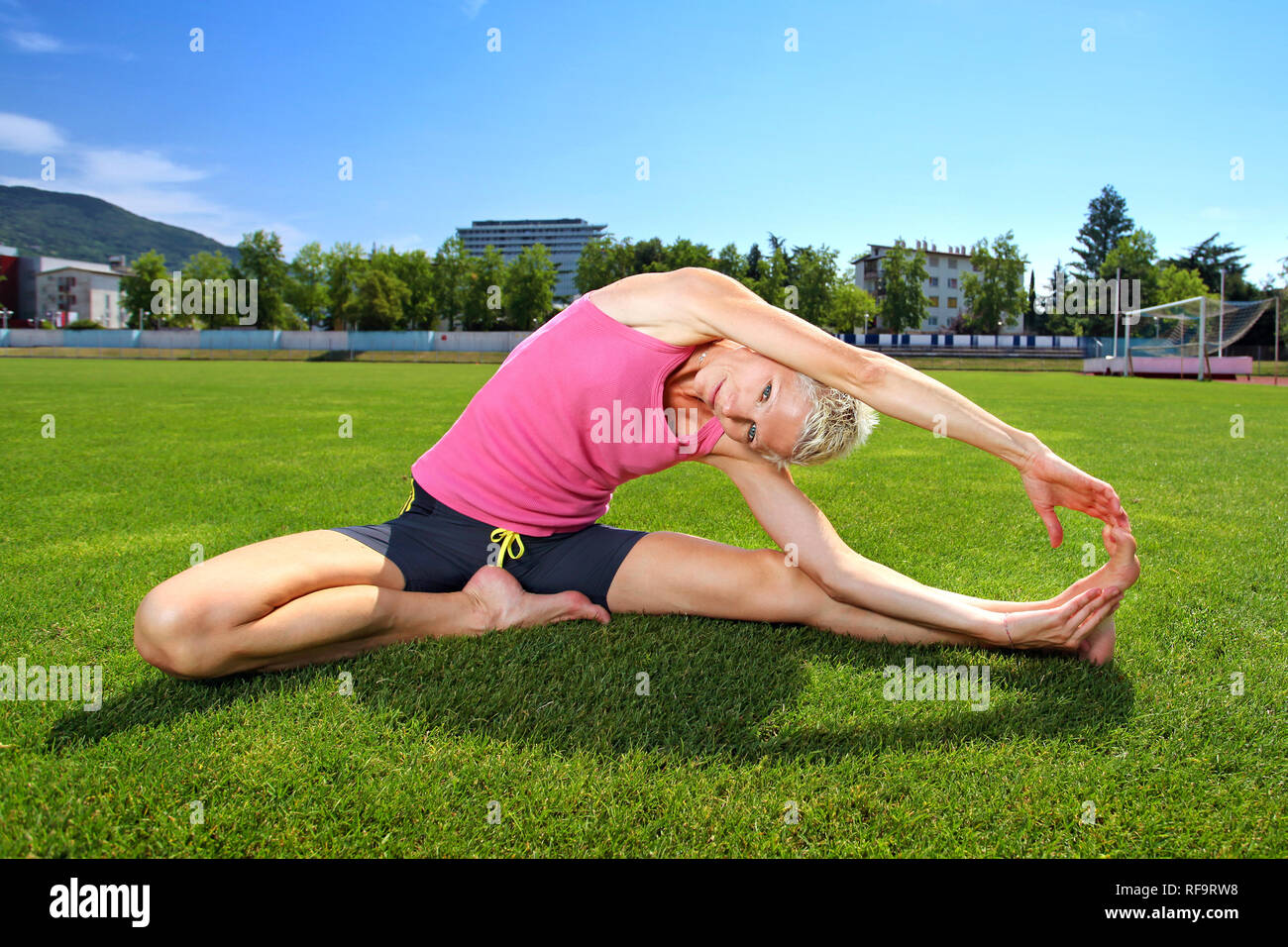 Woman stretching after workout on stadium Stock Photo - Alamy