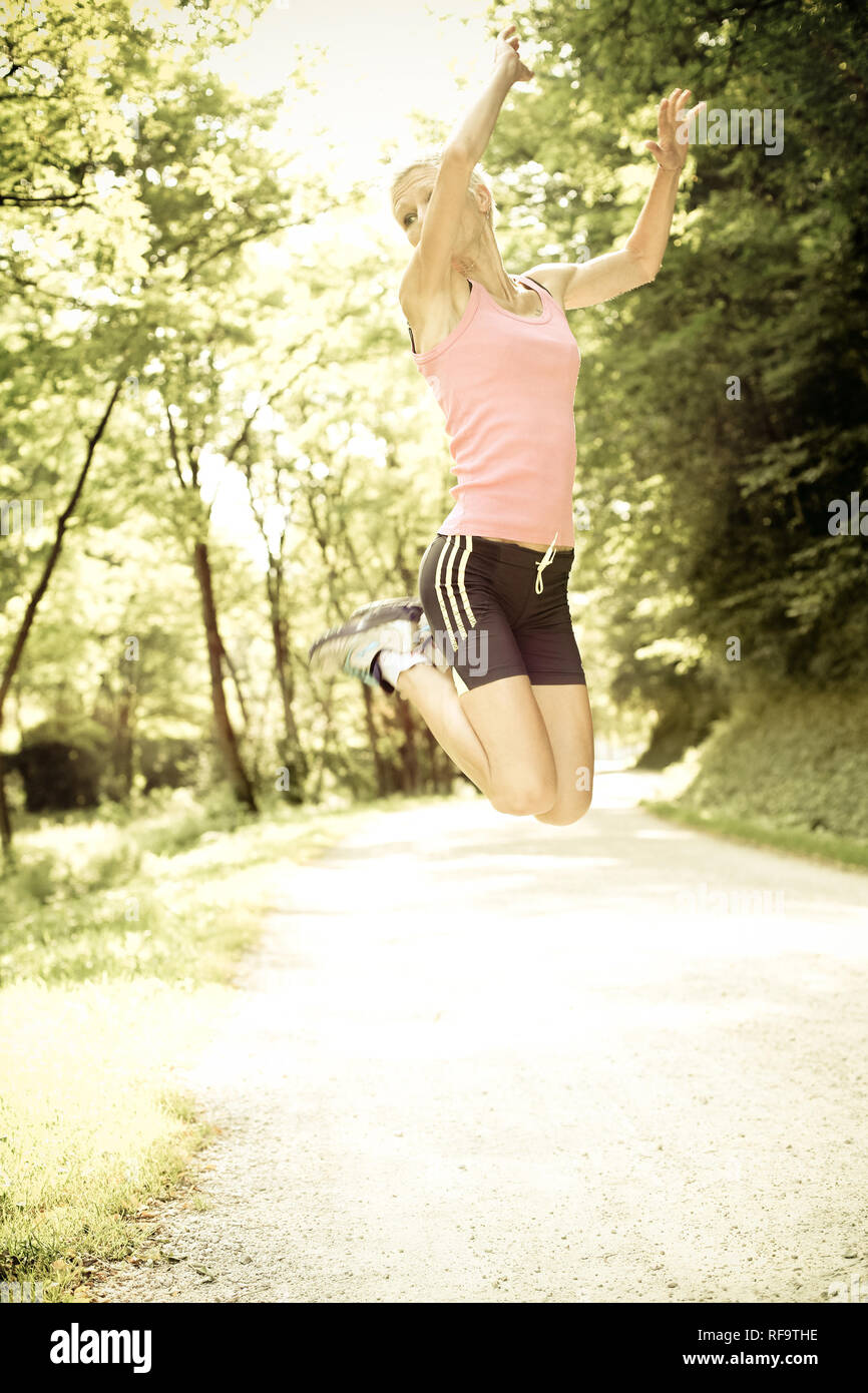Fit caucasian woman jumping in nature Stock Photo - Alamy