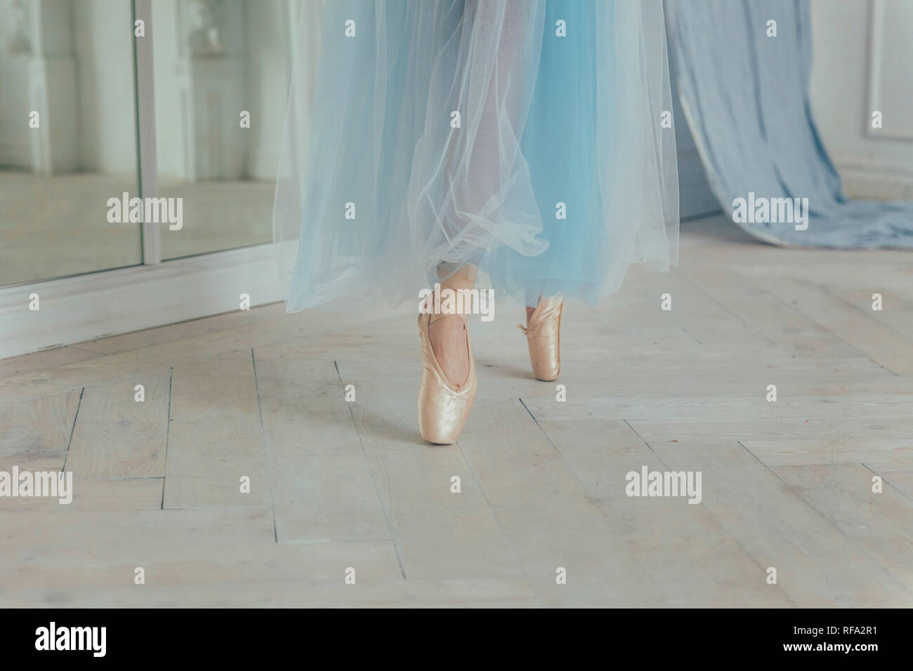 Hands of ballerina in blue tutu skirt puts on pointe shoes on leg in ...