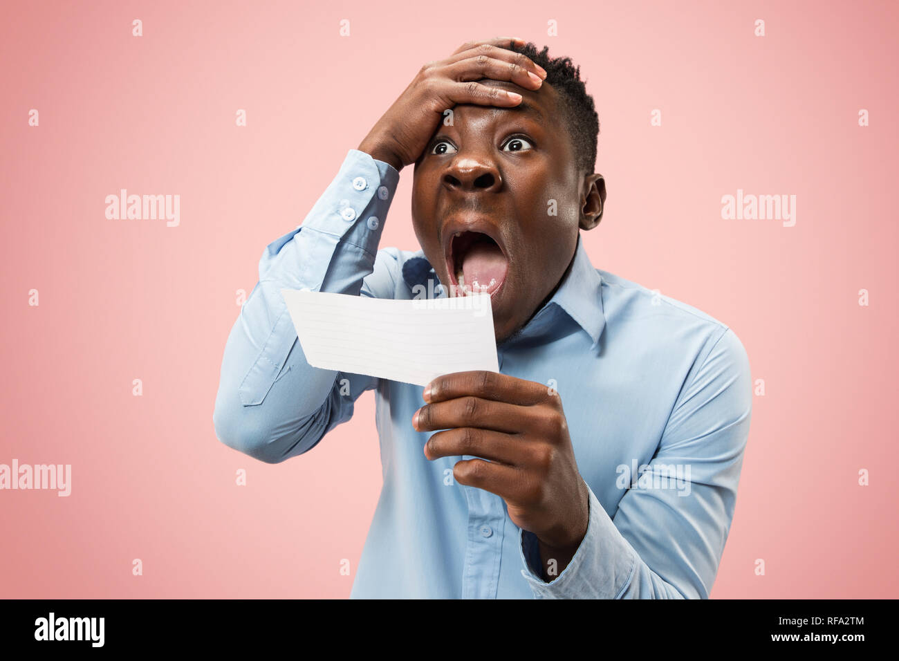 Young afro man with a surprised unhappy failure expression bet slip ...