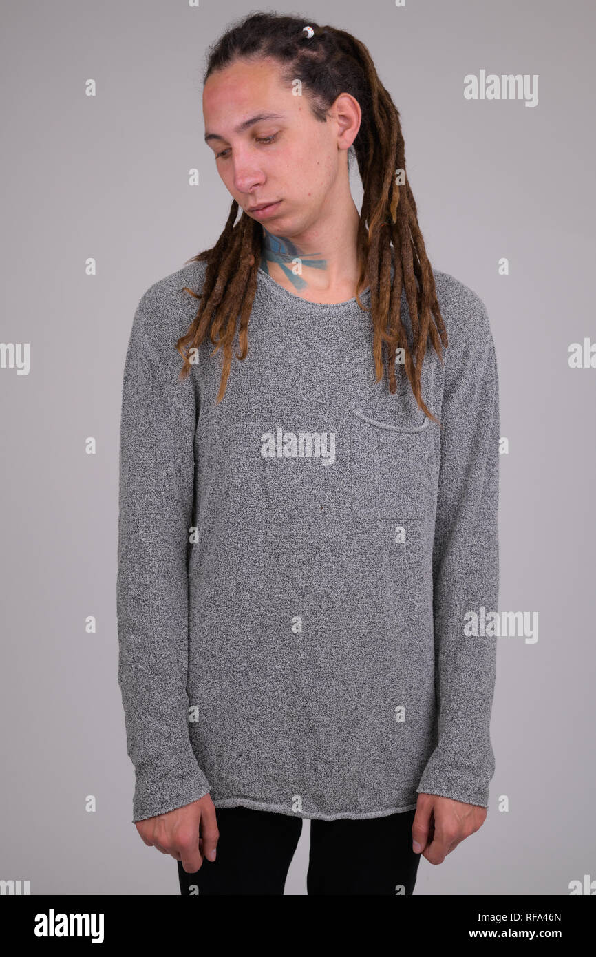 Portrait of sad young man with dreadlocks thinking and looking down ...