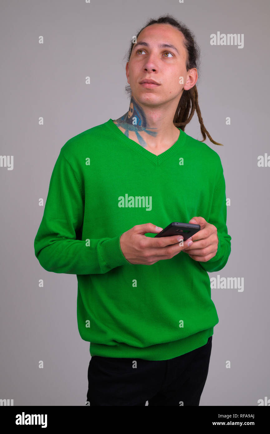 Portrait of young man with dreadlocks thinking while using phone Stock ...