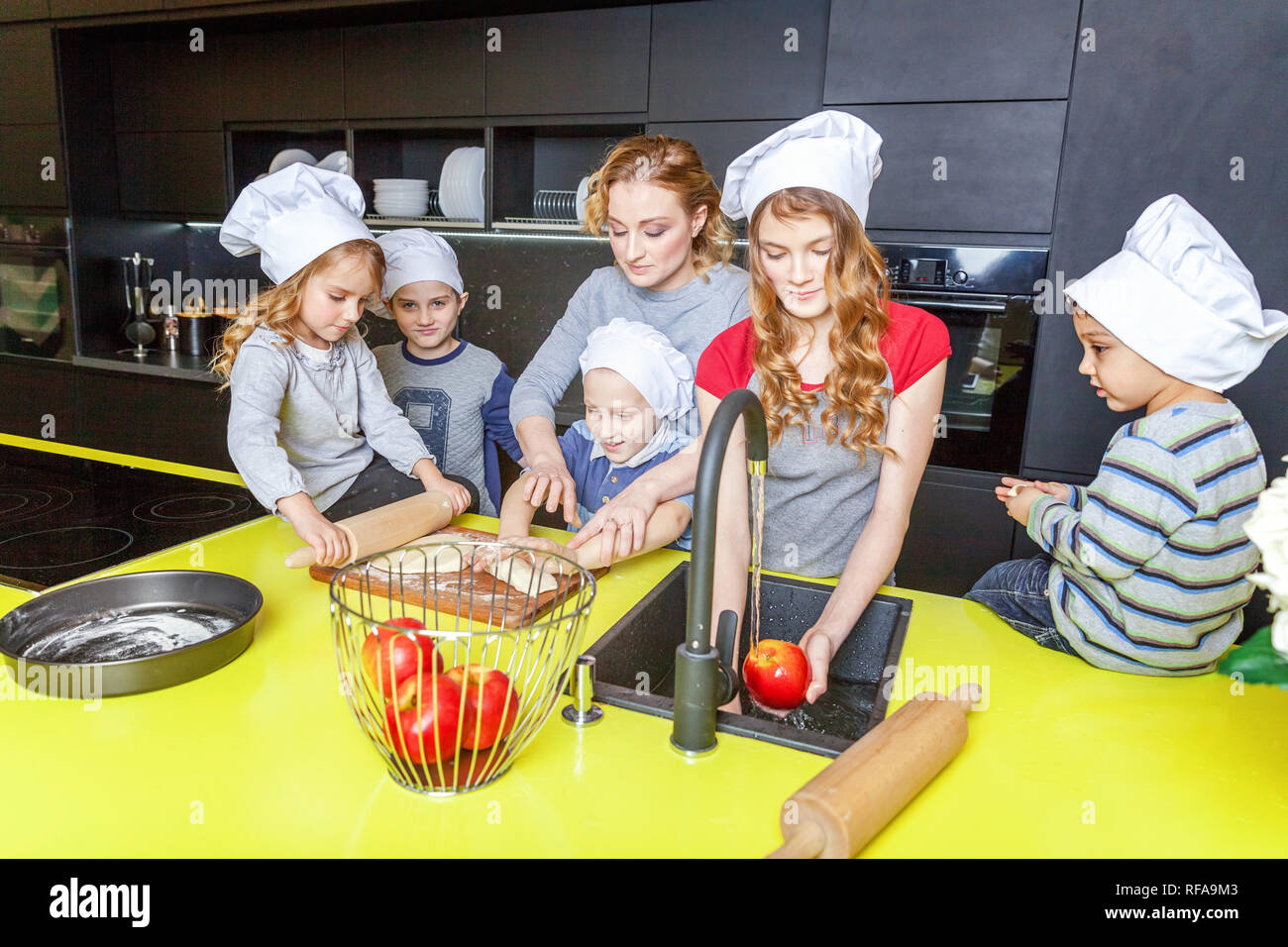 Happy family in kitchen. Mother and five children preparing dough, bake ...