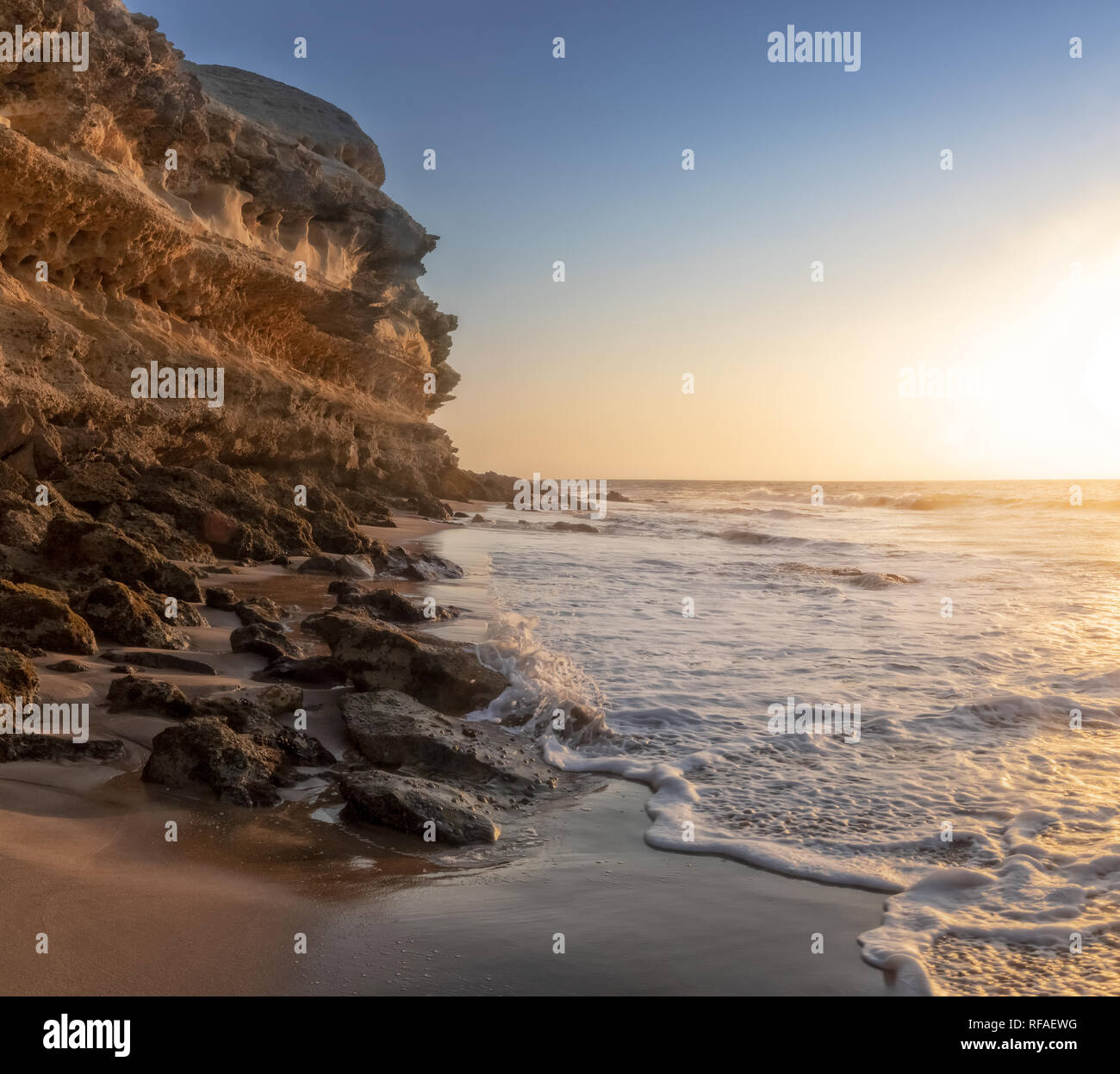 Beautiful sunset with cliff and rocky beach on deserted Namibe beach ...
