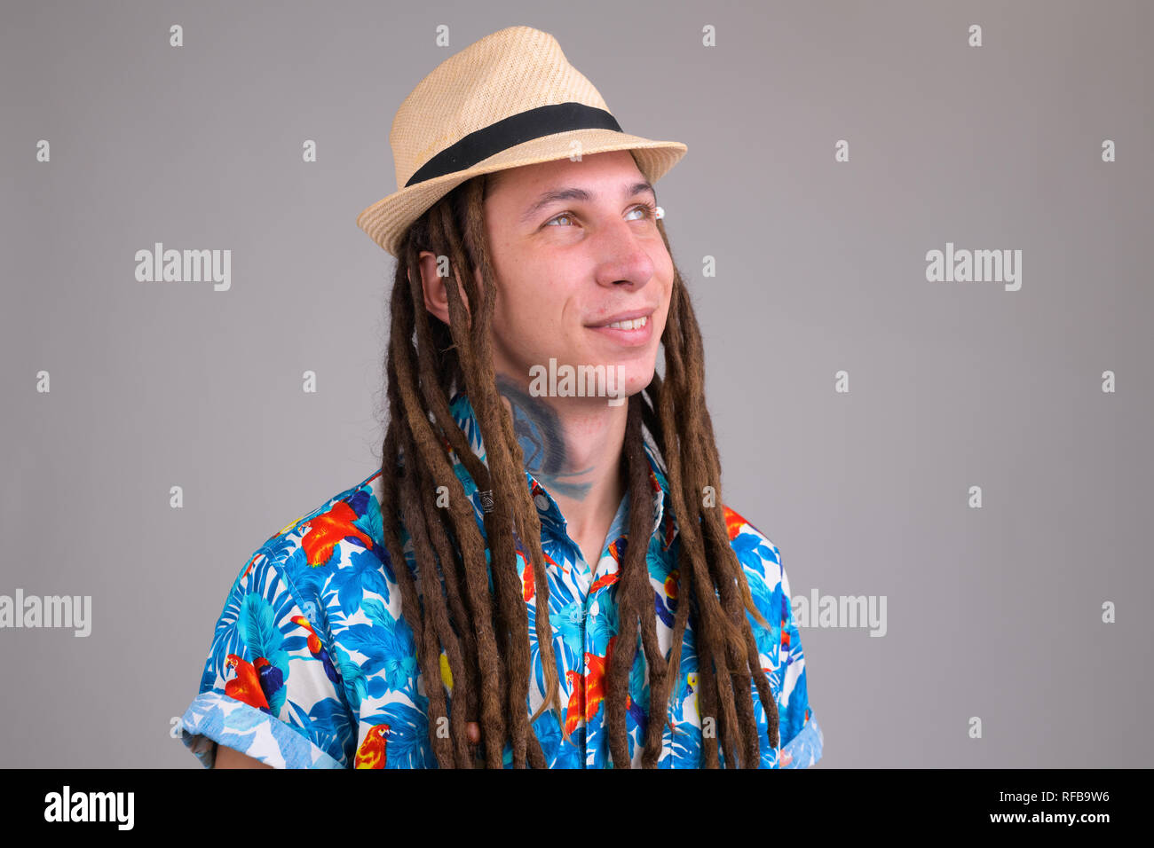 Face of young happy tourist man with dreadlocks thinking Stock Photo ...