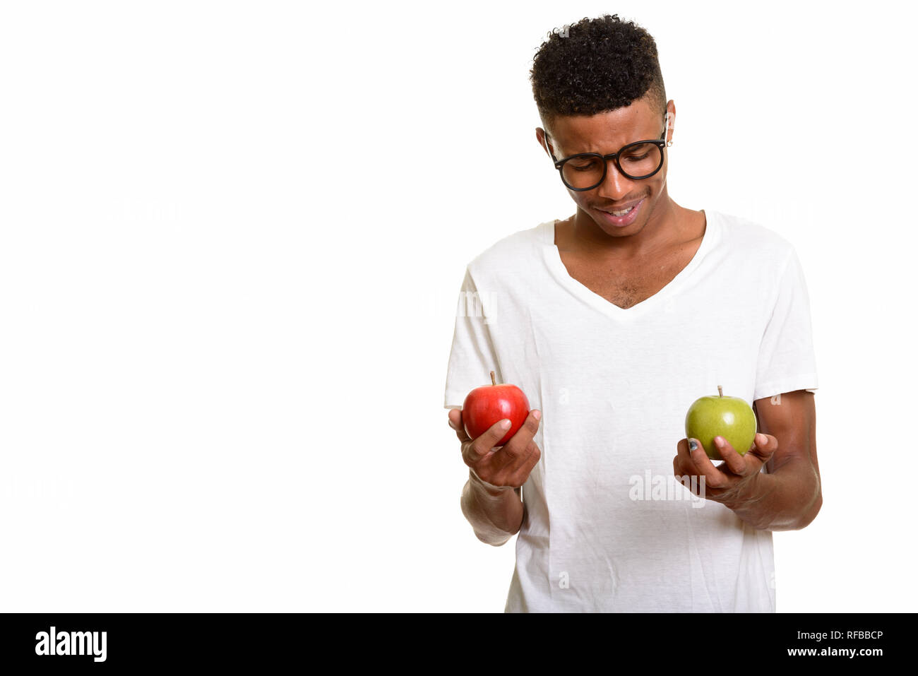 Young happy African man choosing between red and green apple Stock ...