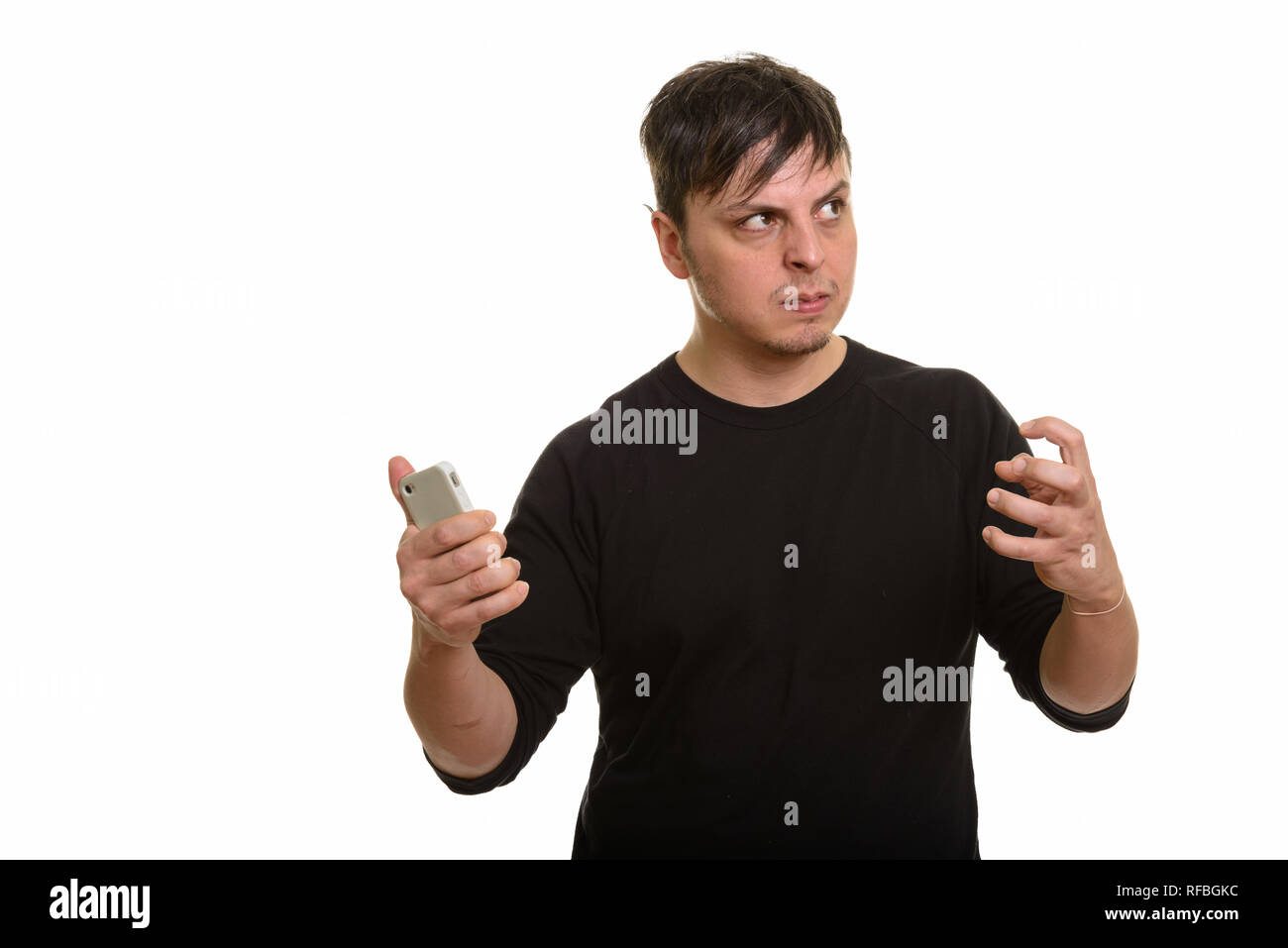 Studio shot of angry Caucasian man hoding mobile phone while thi Stock ...
